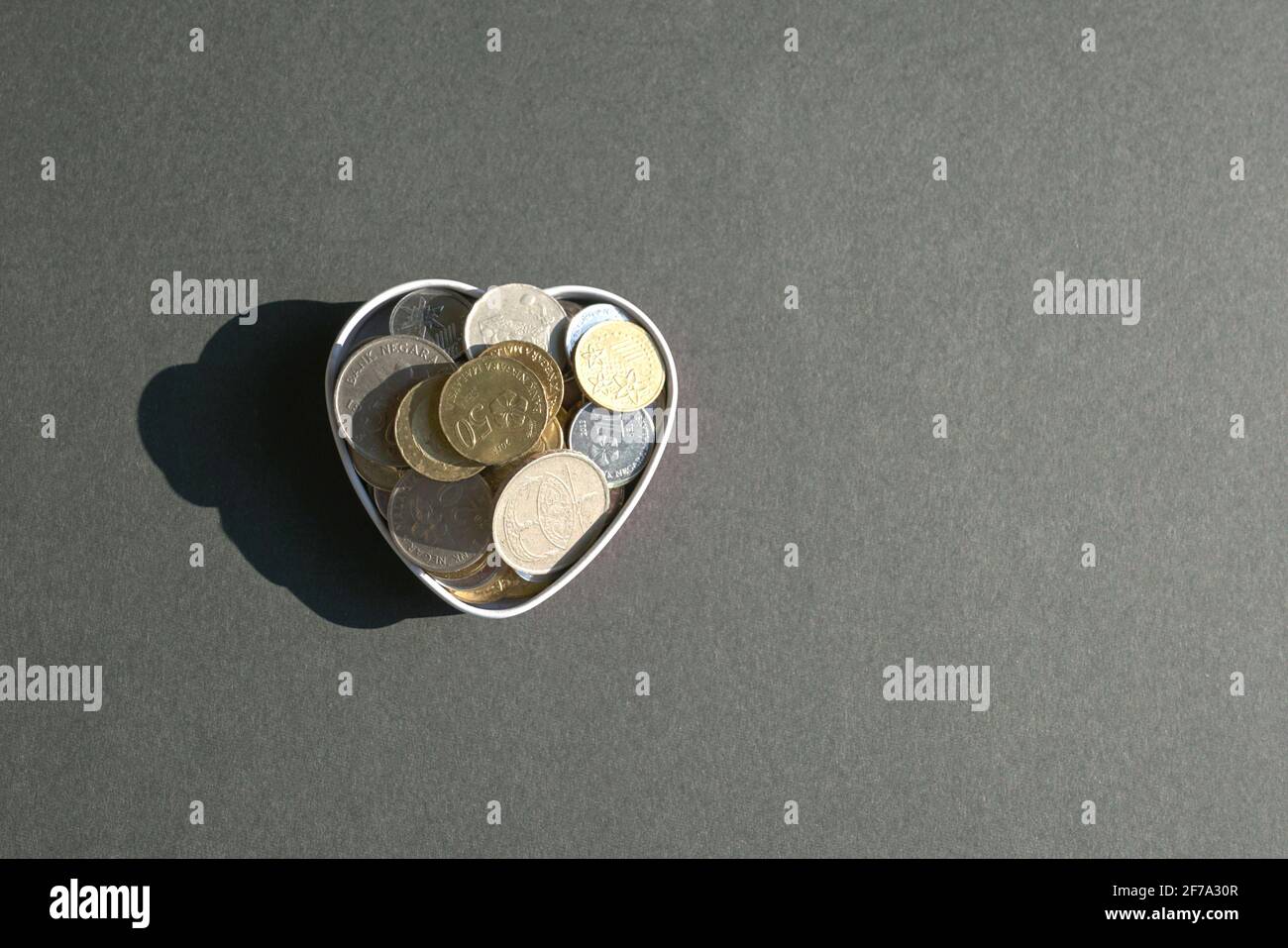 Coins in heart shaped container. Love for money concept. Top view with ...