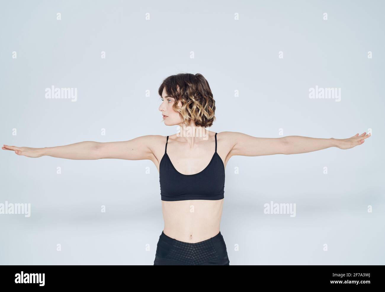 Woman spreads her arms to the sides on a light background sportswear ...