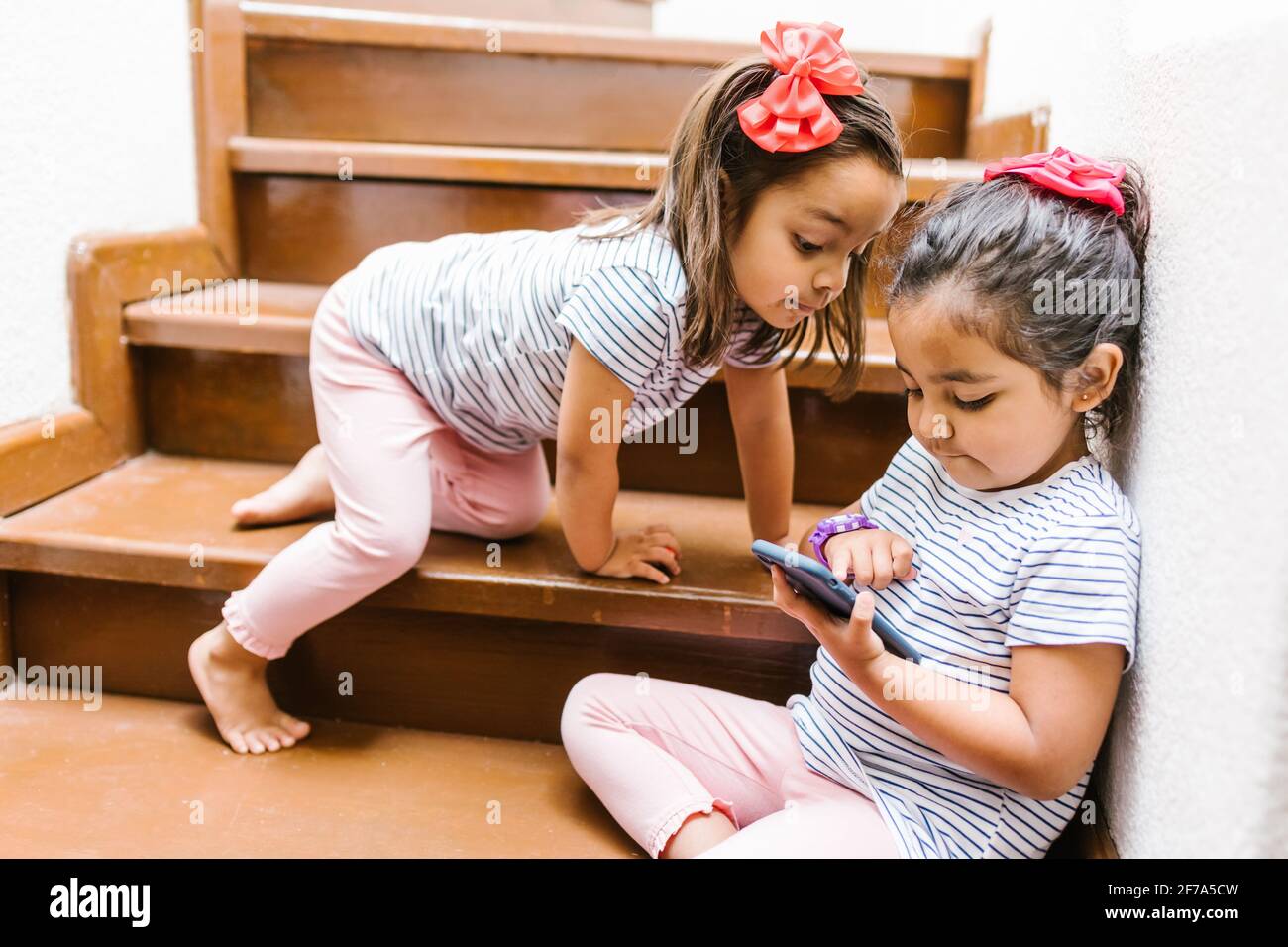 latin child or little girls with phone and tablet at home in Mexico ...