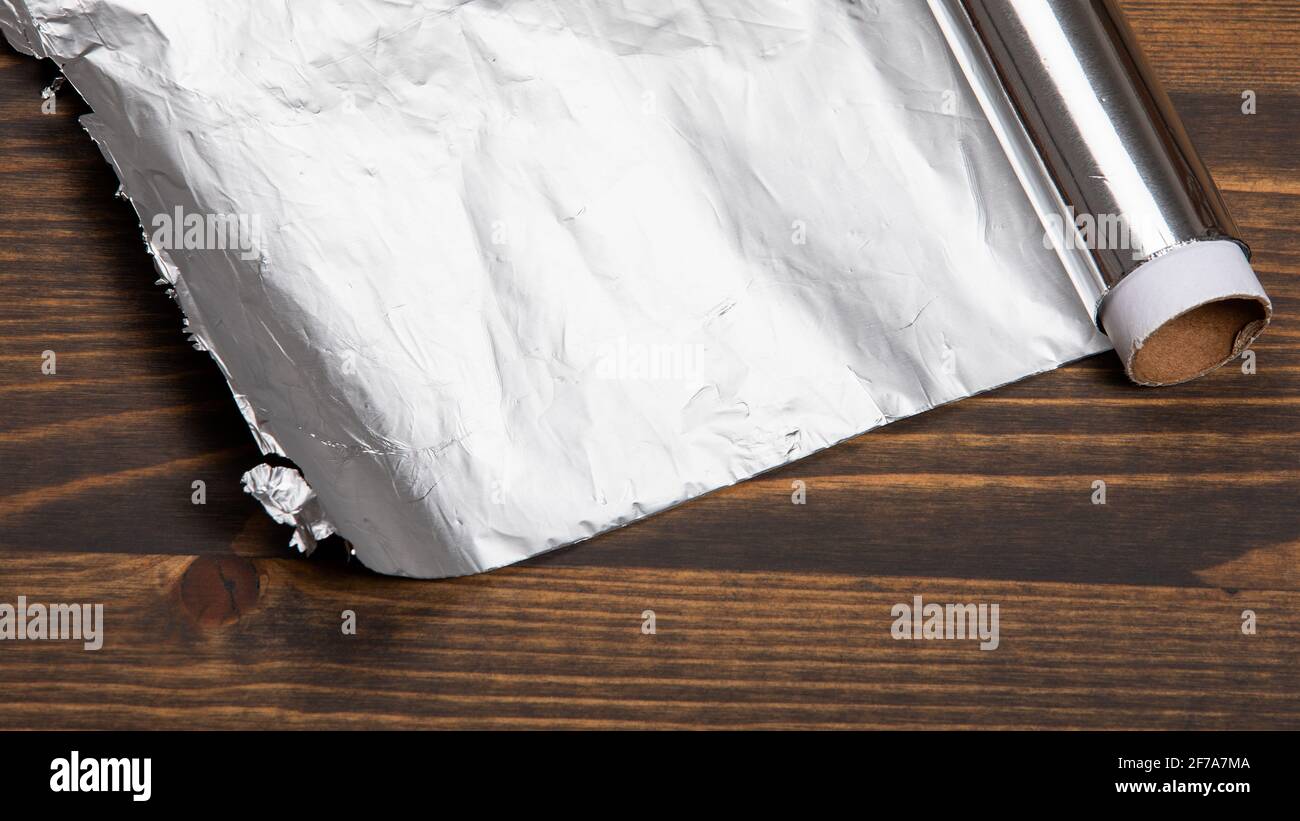Aluminium foil roll on wooden table. For cooking Stock Photo - Alamy