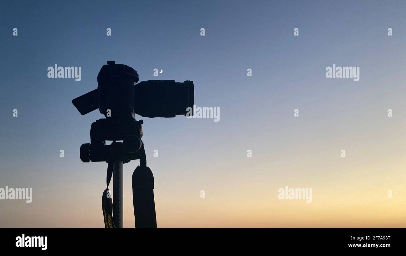 Side profile of a DSLR camera on a tripod during sunrise Stock Photo ...
