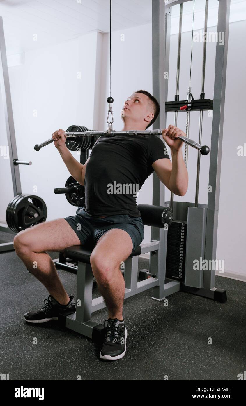 A man trains in the gym on a simulator, does exercises for different ...