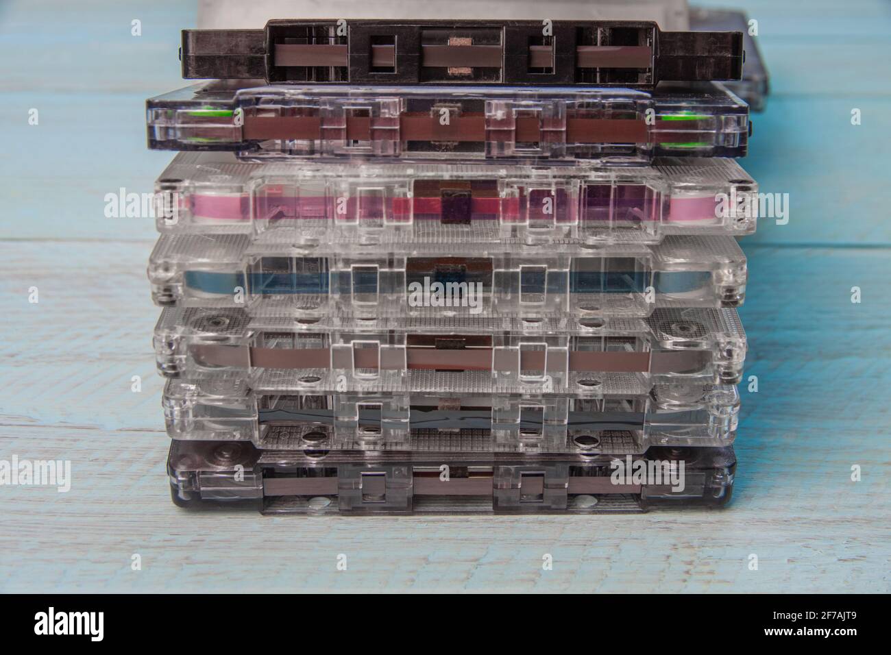 A stack of audio cassettes on a blue wooden background. You can see the ...