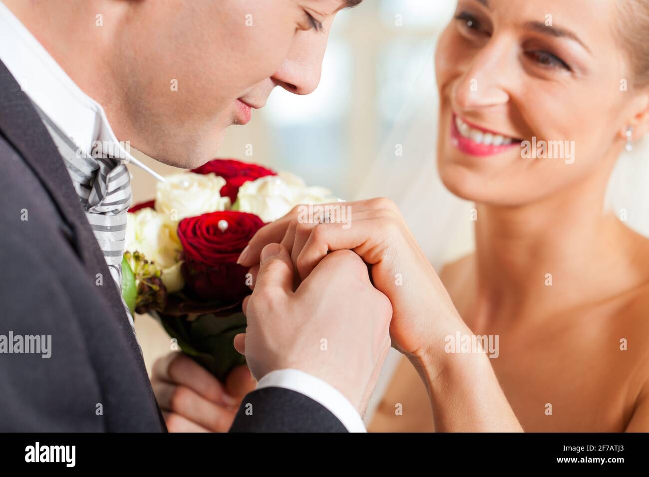 Wedding couple giving promise of marriage; the groom is kissing the ...