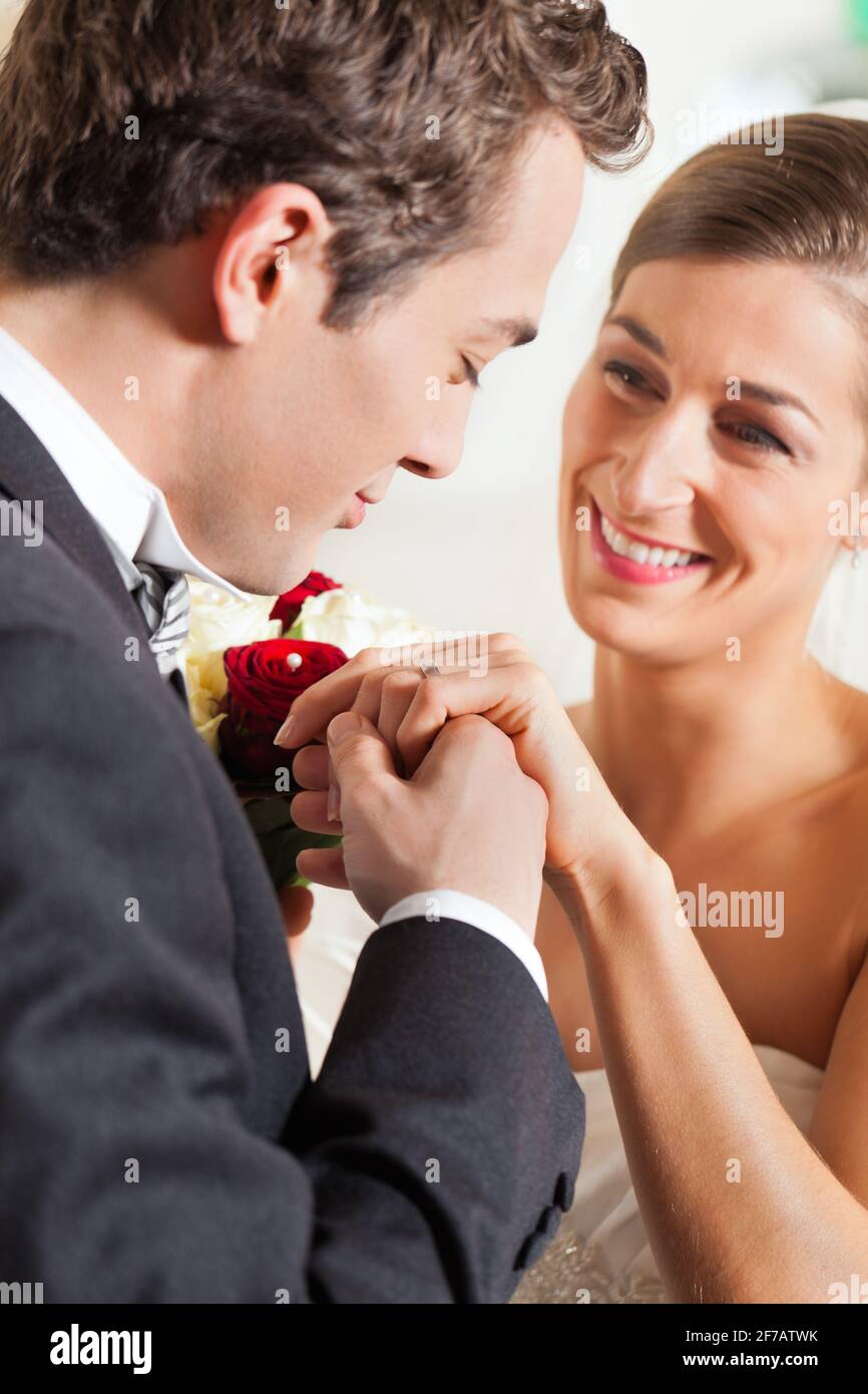 Wedding couple giving promise of marriage; the groom is kissing the ...