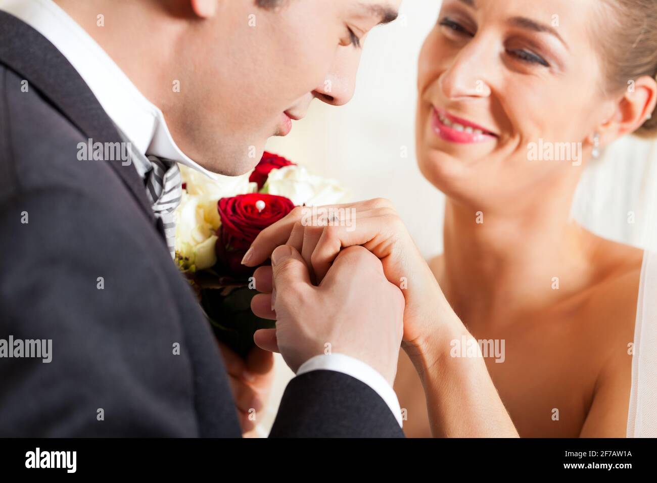 Wedding couple giving promise of marriage; the groom is kissing the ...