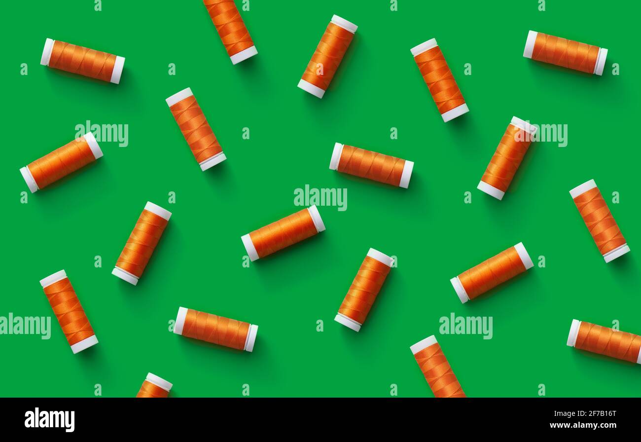Flat lay pattern of spools of thread on green background. Top view ...