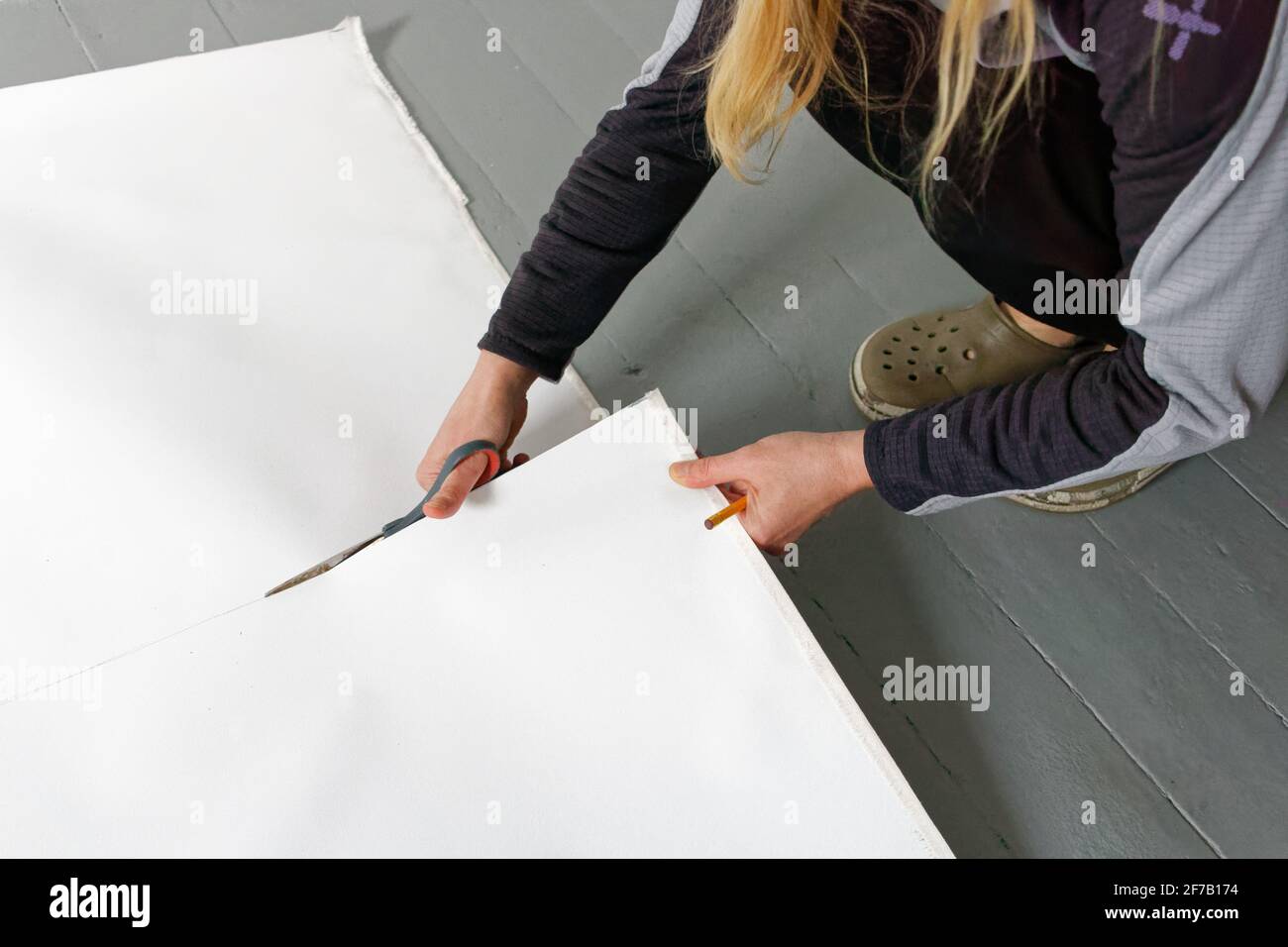 A female artist cutting canvas to prepare her own picture supports ...