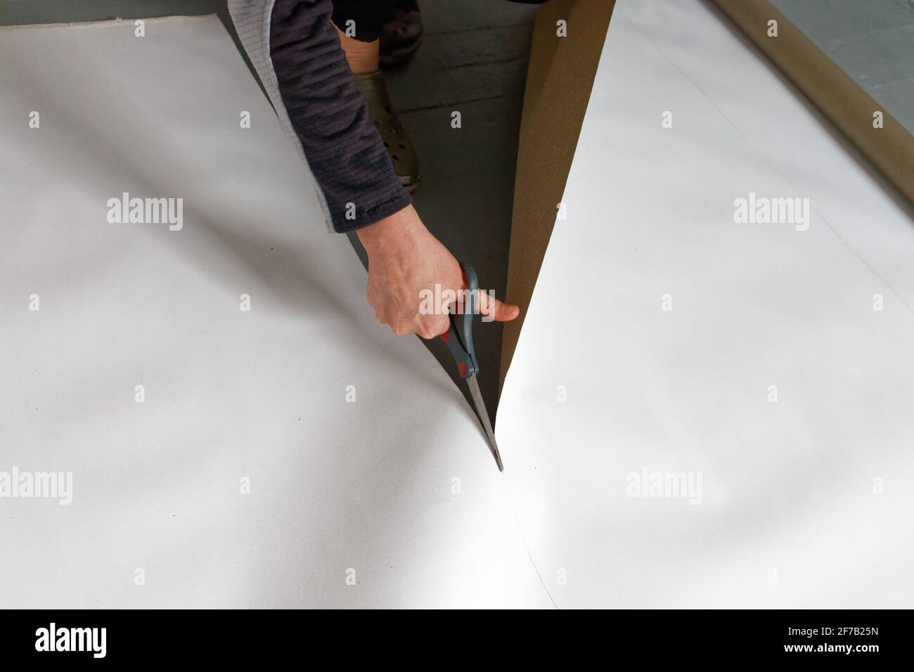 A female artist cutting canvas to prepare her own picture supports ...
