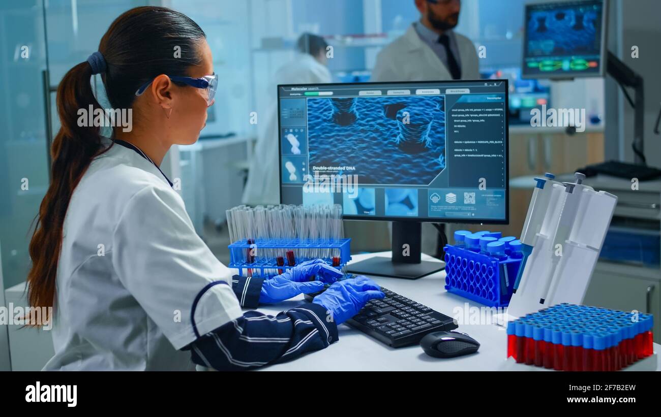 Woman technologist doing a laboratory test examining a flask with blood ...