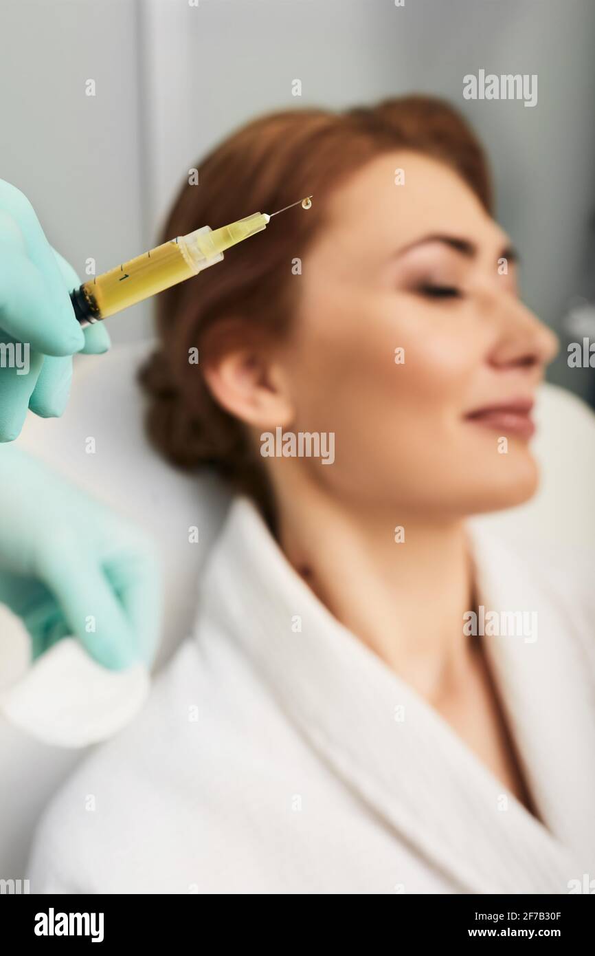 Syringe with a patient's blood plasma in a cosmetologist's hand for a ...