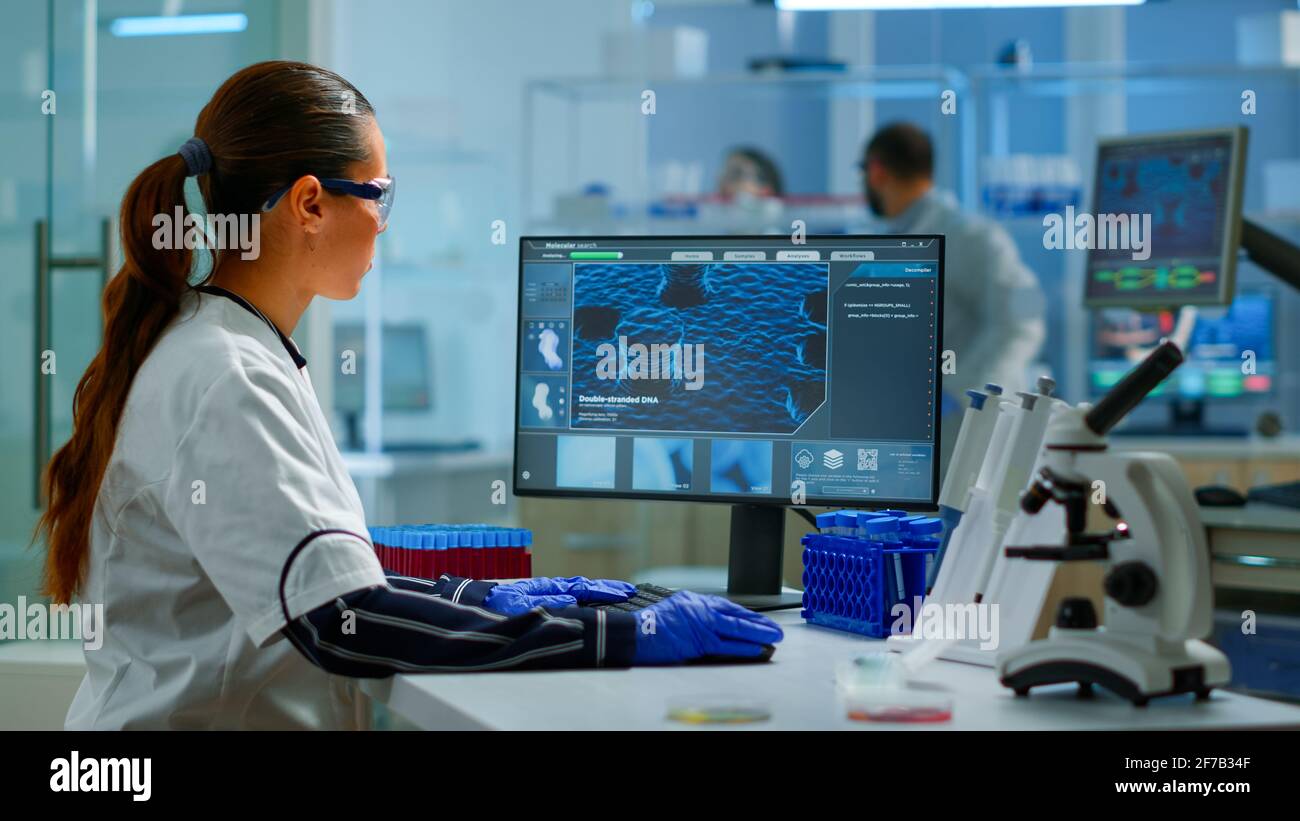 Biologist doctor checking DNA informations typing on pc in modern ...