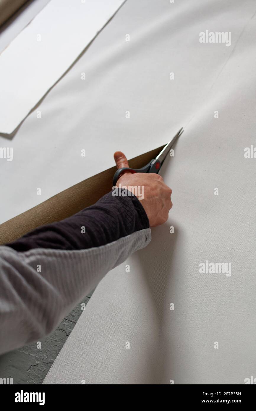 A female artist cutting canvas to prepare her own picture supports ...