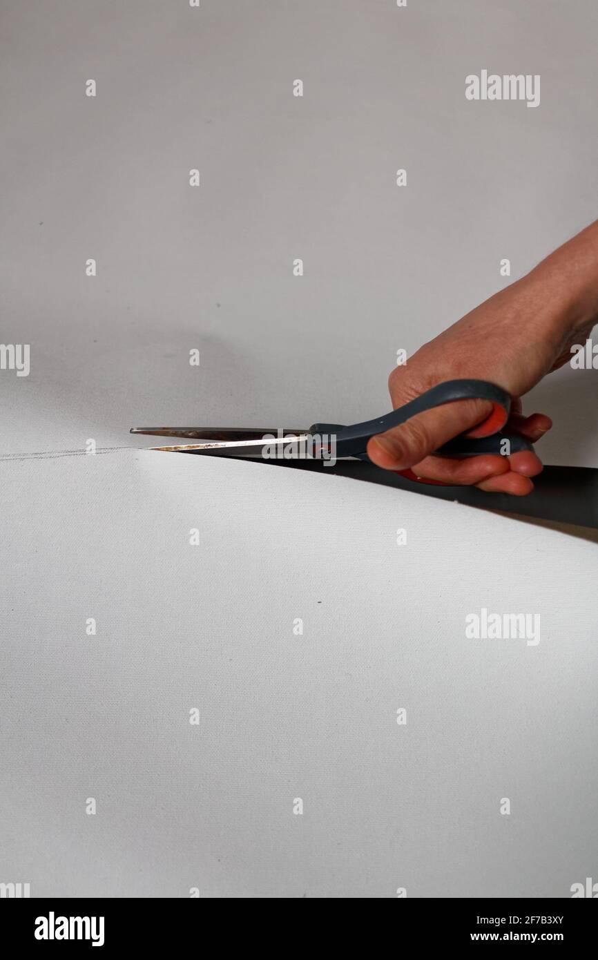 A female artist cutting canvas to prepare her own picture supports ...