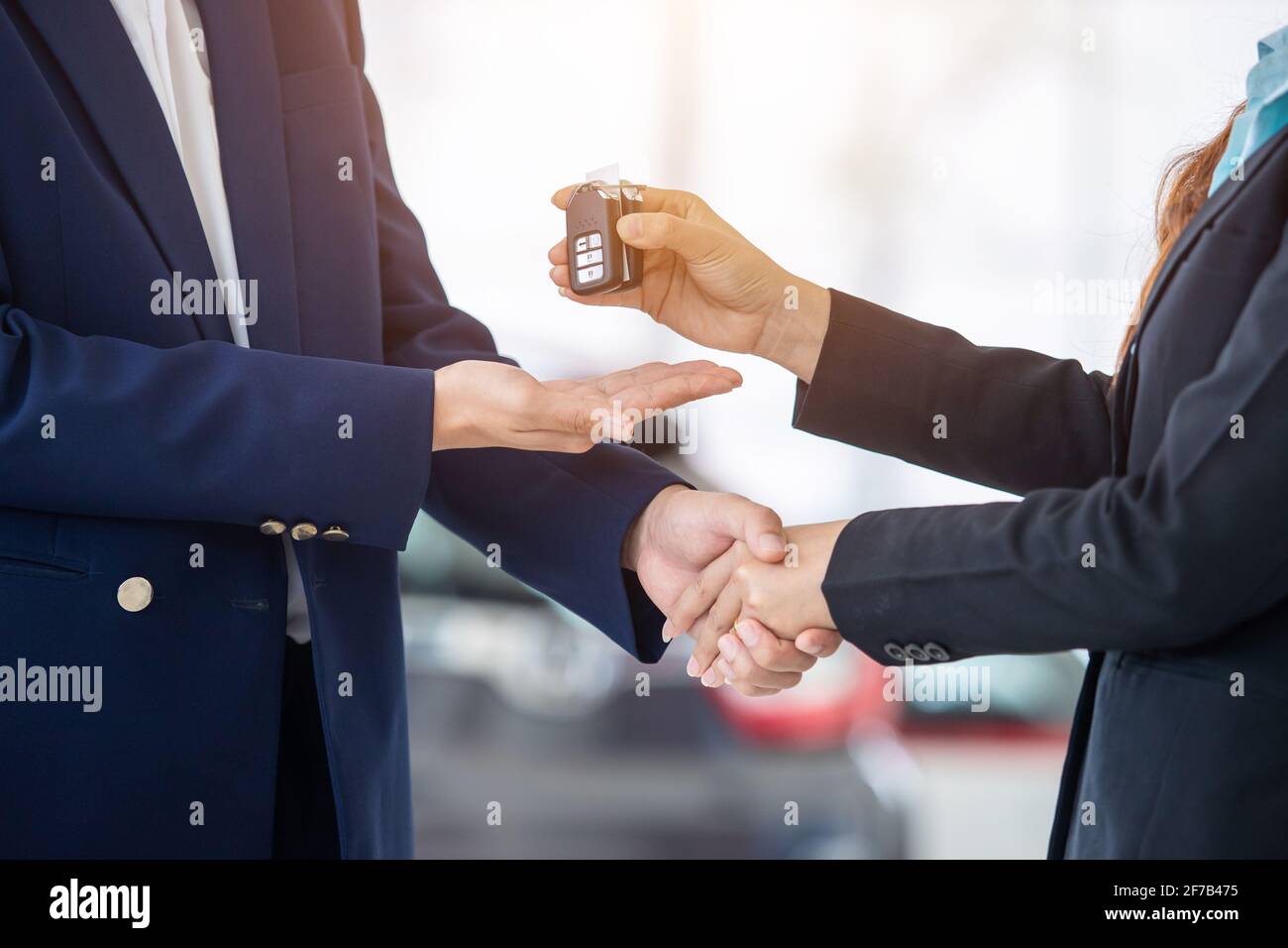 hand of car sales woman giving the key of the new car to the And ...