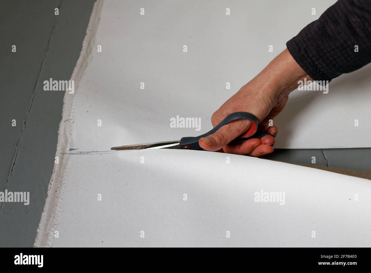A female artist cutting canvas to prepare her own picture supports ...