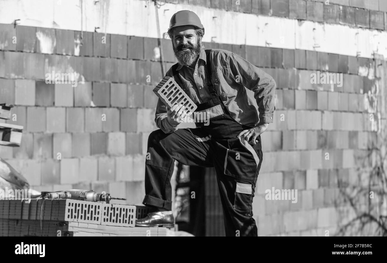 happy bearded man hold brick. brickwork. Man takes brick from the pile ...