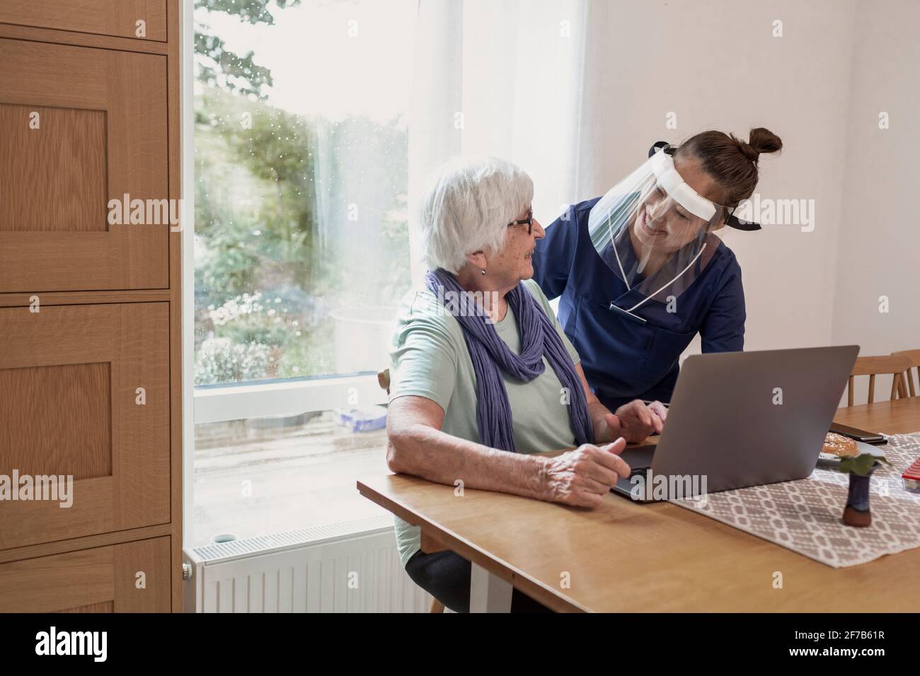 Home carer helping senior woman to use laptop Stock Photo - Alamy