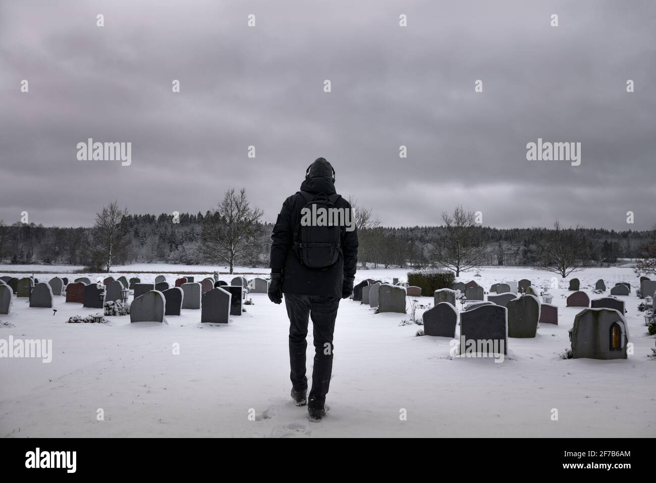 Man walking through snowy cemetery Stock Photo - Alamy