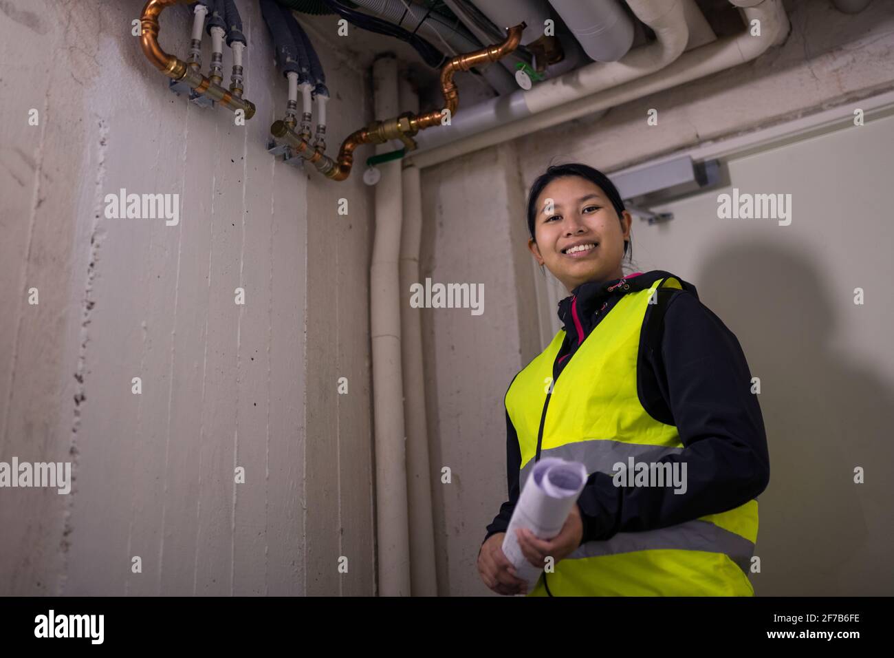 Female plumber holding blueprint and checking pipes Stock Photo - Alamy