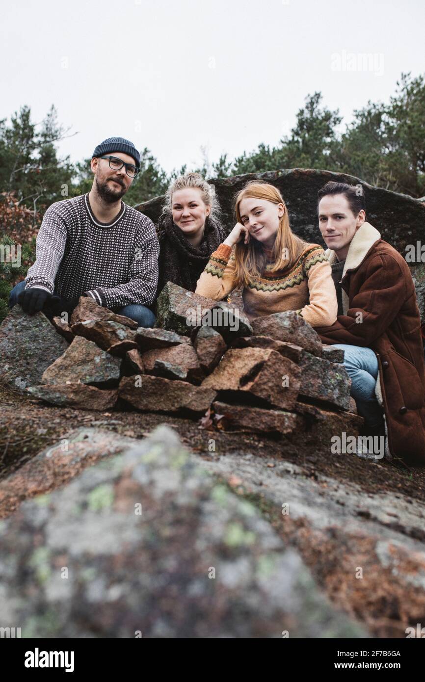 Smiling friends sitting together and looking at camera Stock Photo - Alamy
