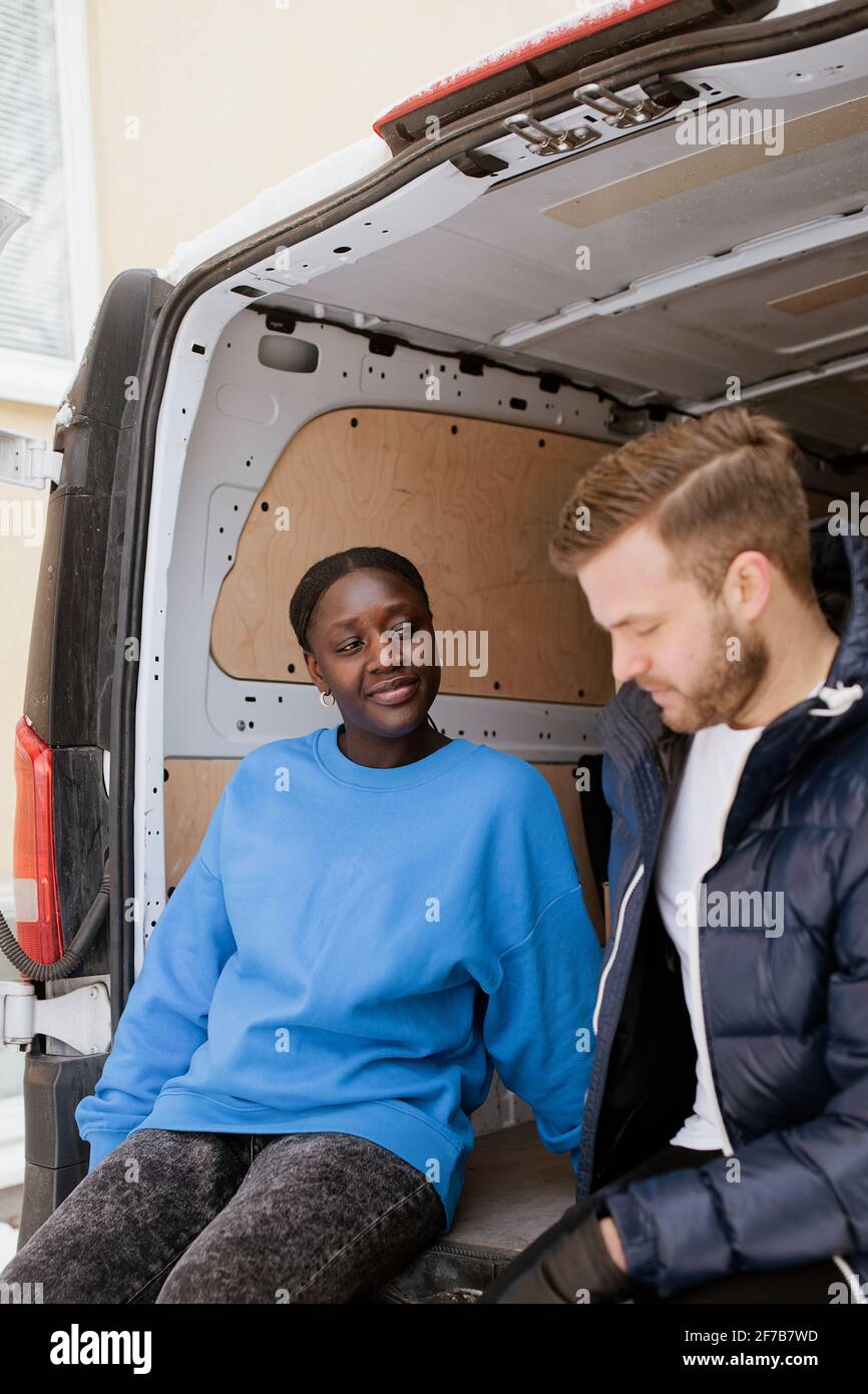 Couple sitting in back of van Stock Photo - Alamy