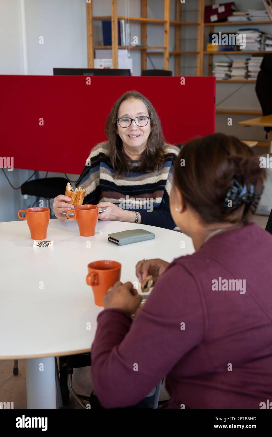 Two women having breakfast in office Stock Photo - Alamy