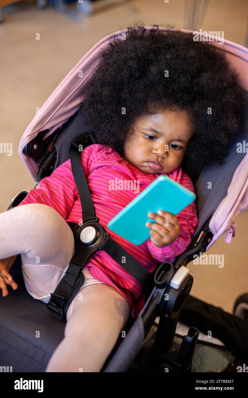 Girl with smartphone sitting in buggy Stock Photo - Alamy