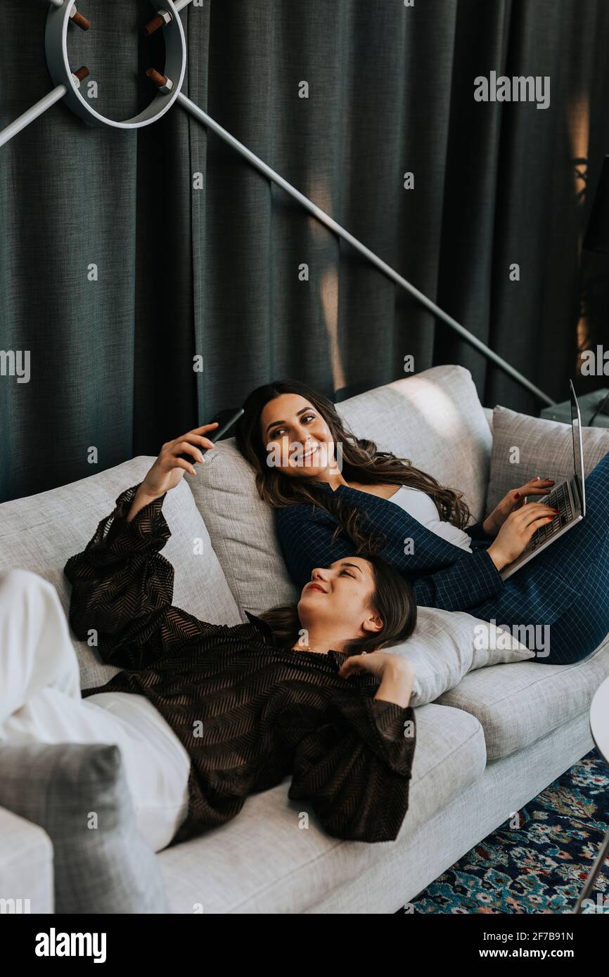 Female coworkers working on sofa Stock Photo - Alamy