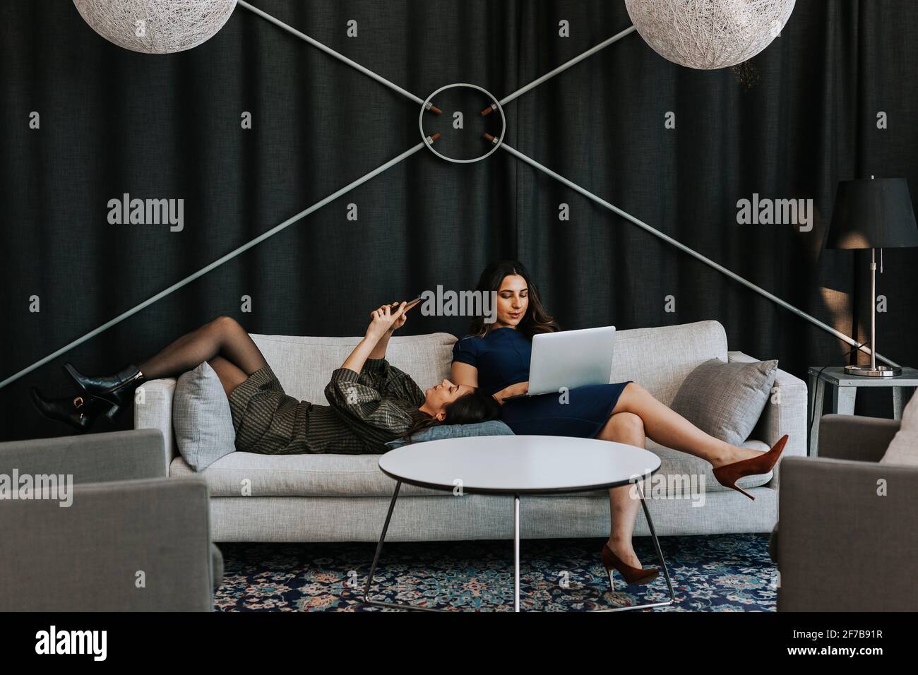 Female coworkers working on sofa Stock Photo - Alamy