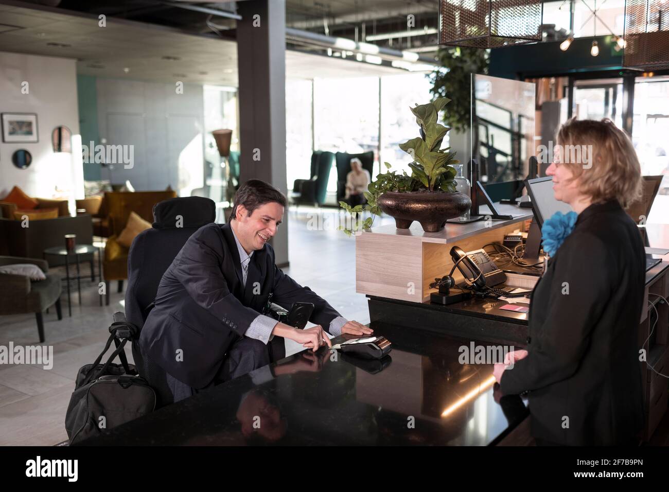 Businessman on wheelchair at hotel reception desk Stock Photo - Alamy