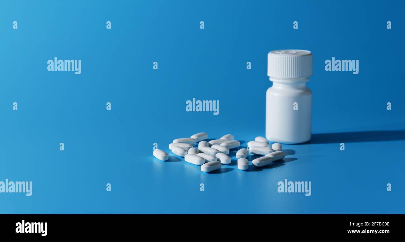 Medical white bottle and pills on blue background. Banner. Copy space ...