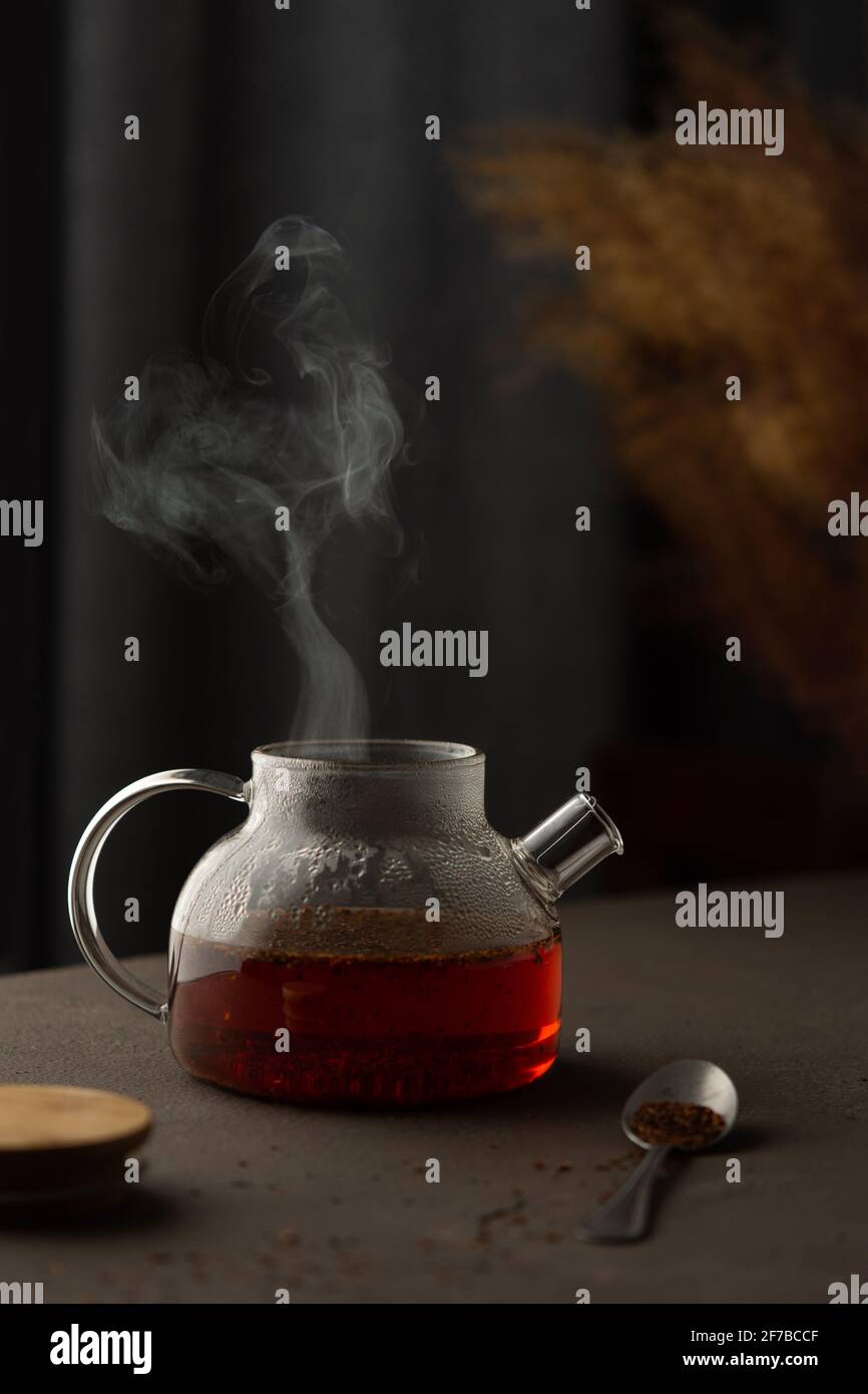 The process of brewing rooibos tea with herbs, glass teapot with ...