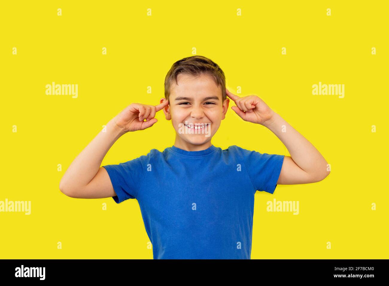 boy 6 years old in blue t-shirt on yellow background, foolish funny ...