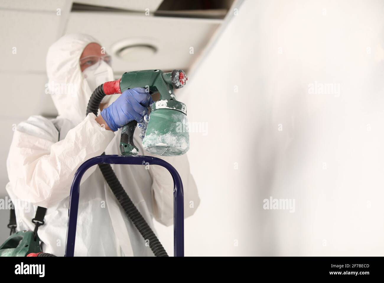 Master painter in protective suit is touching wall with spray gun Stock ...