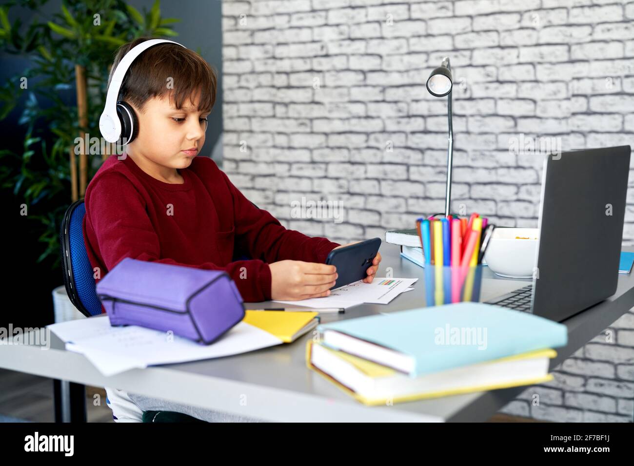 Boy playing on the mobile phone during online classes Stock Photo - Alamy