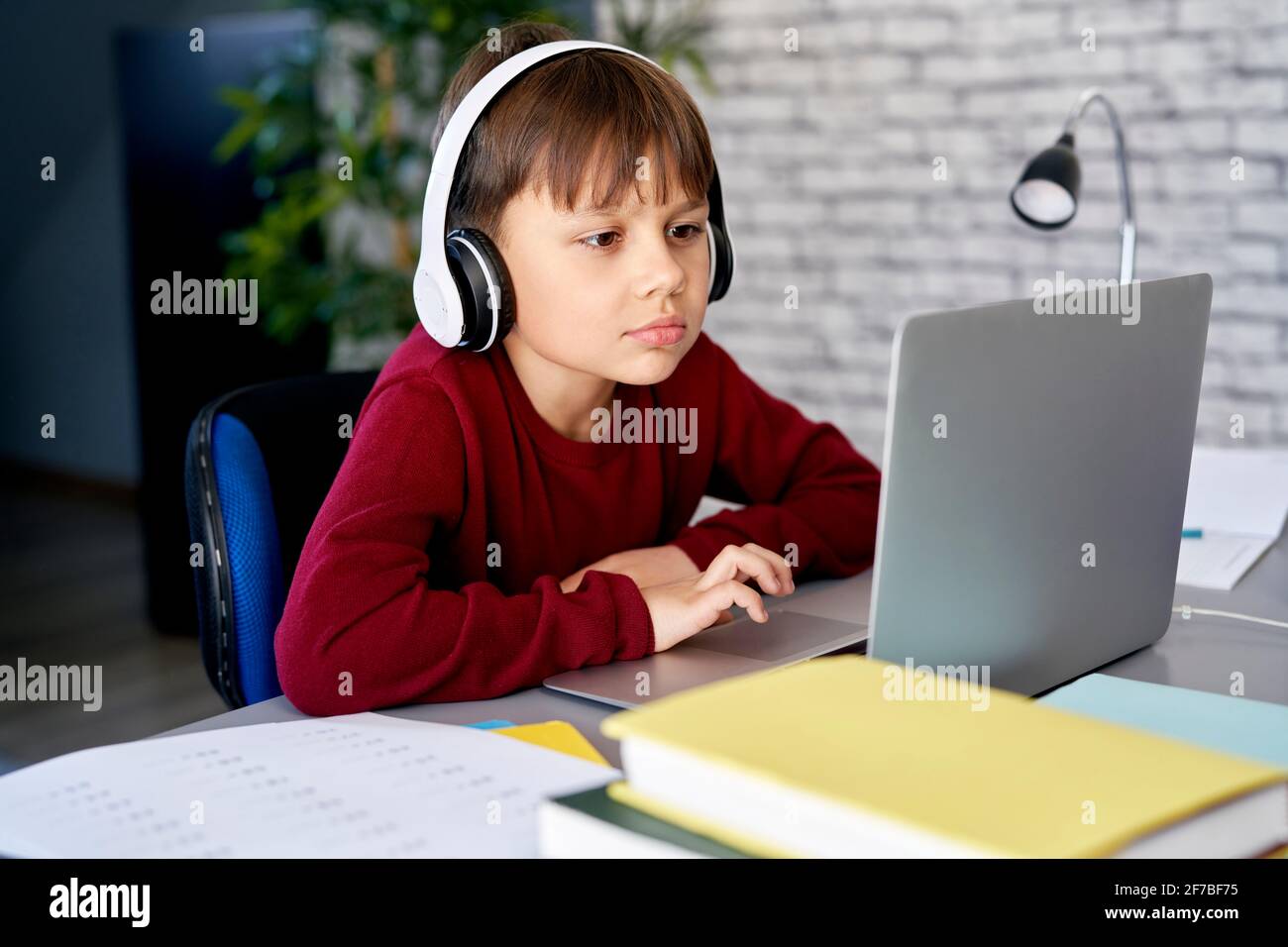 Concentrated boy in headphones while studying at home Stock Photo - Alamy