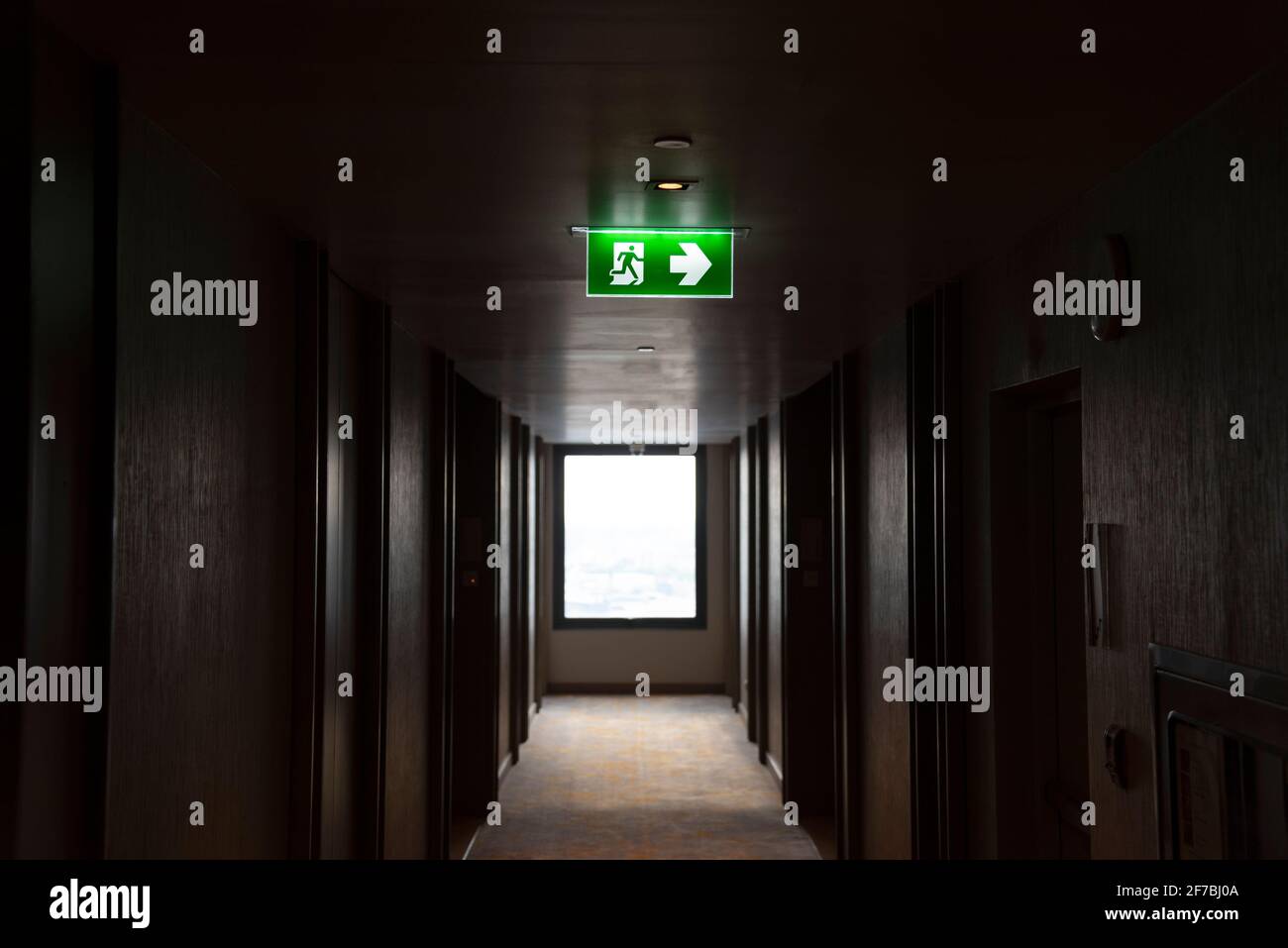 Illuminated green light emergency exit sign in public building for ...