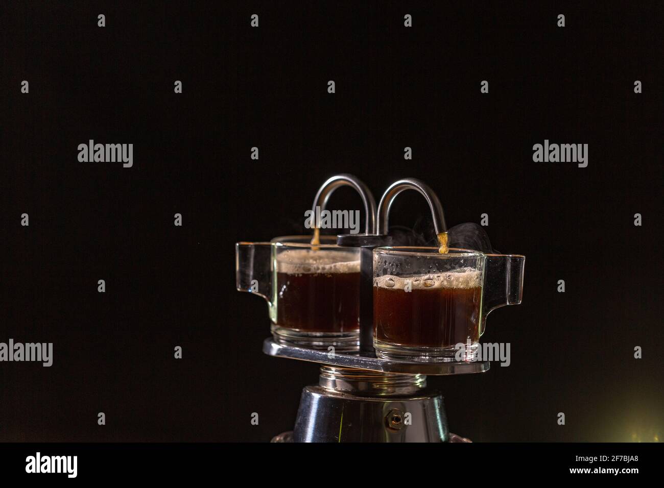 Heat vapor emitted from the coffee machine. Two black coffeemakers in a ...