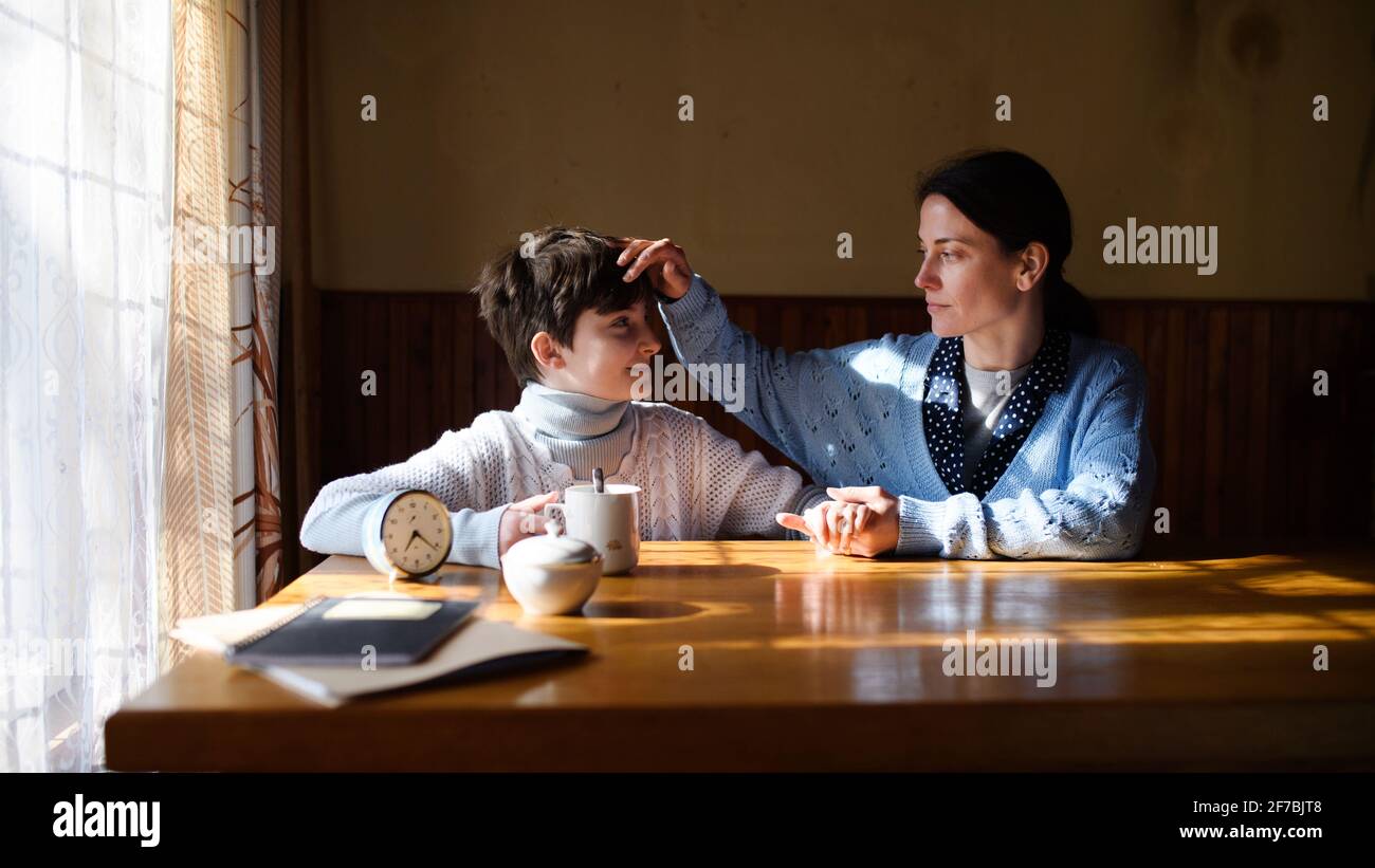 Portrait of sad poor mature mother with small daughter indoors at home ...