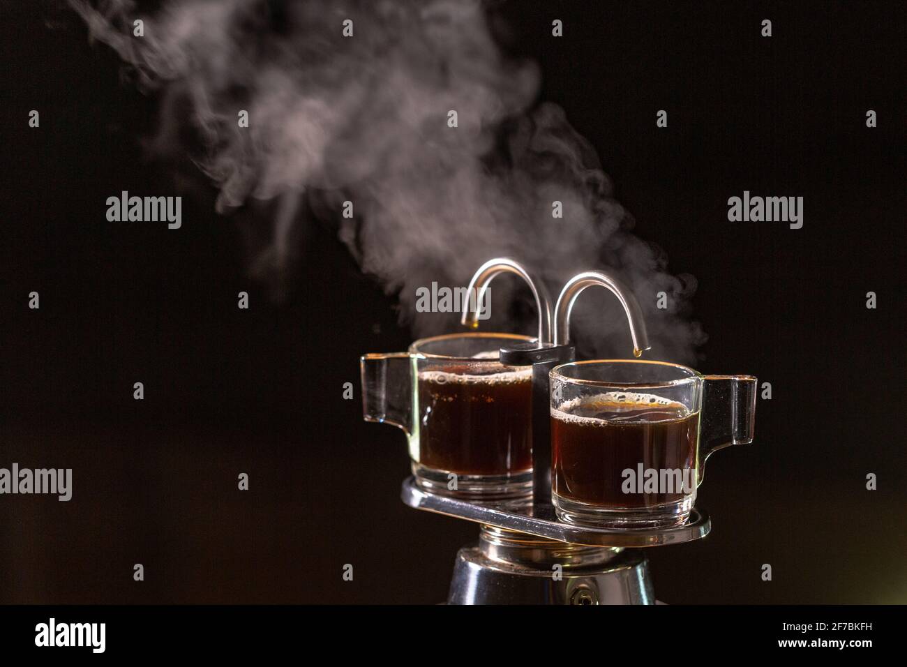 Heat vapor emitted from the coffee machine. Two black coffeemakers in a ...
