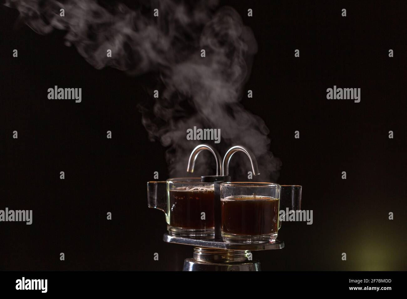 Heat vapor emitted from the coffee machine. Two black coffeemakers in a ...