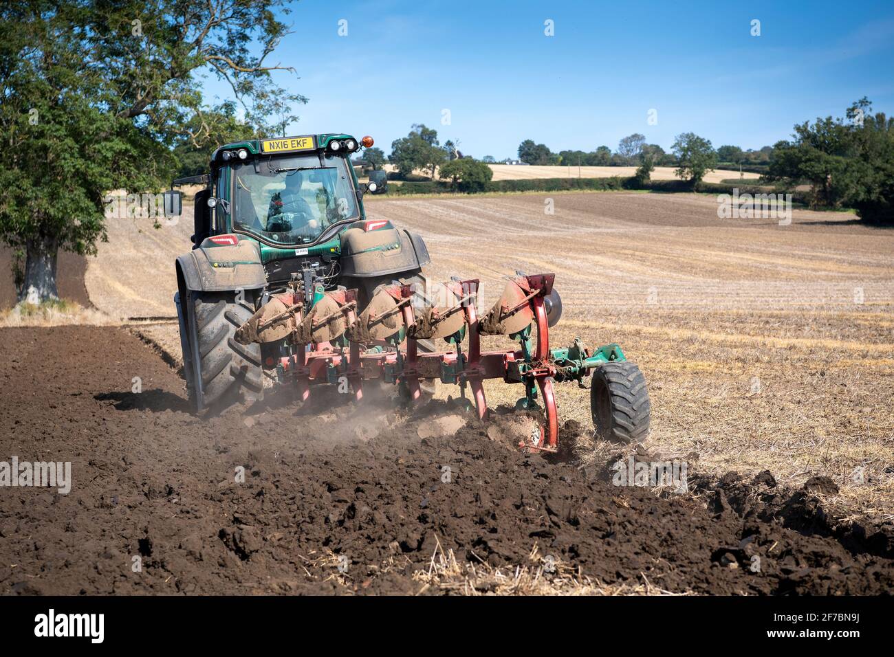Farmer ploughing in stubble after taking crop off, using a Valtra ...