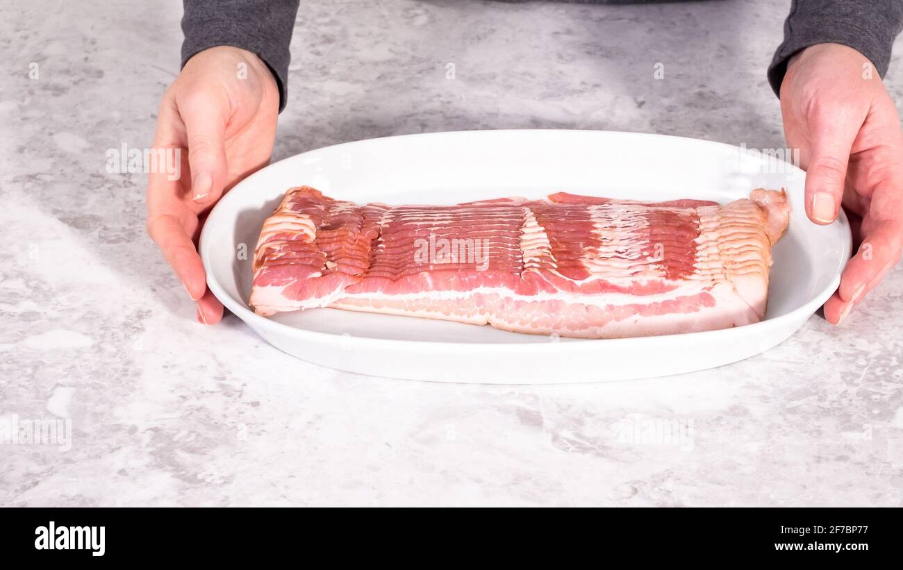 Step by step. Uncooked bacon strips on a large white plate Stock Photo ...