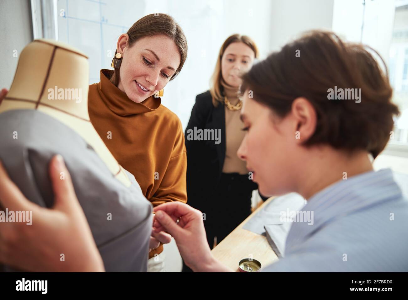 Two females sticking pins to fabric on tailor bust Stock Photo - Alamy