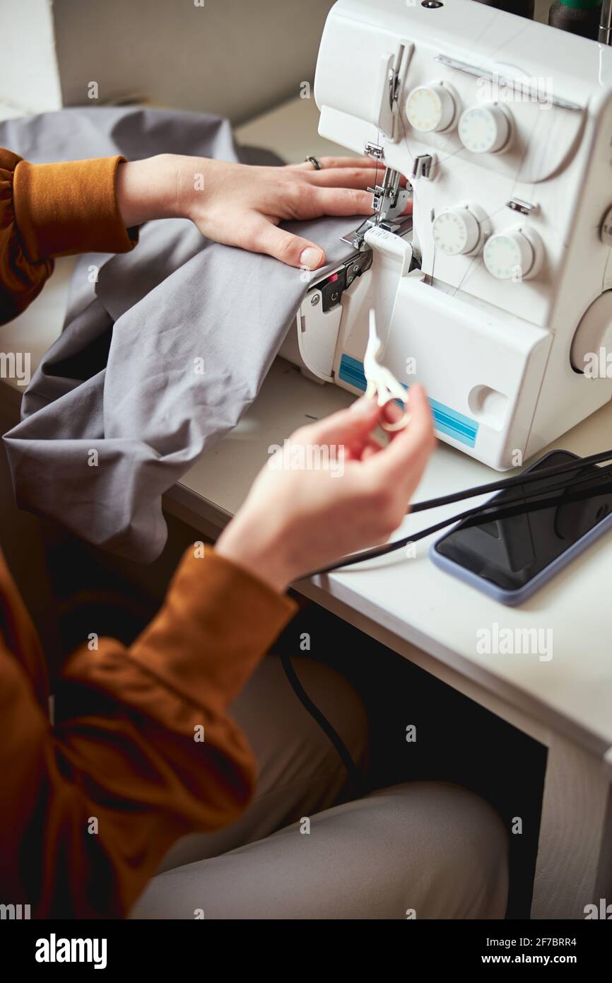 Adult stitching cloth with machine while keeping embroidery scissors ...