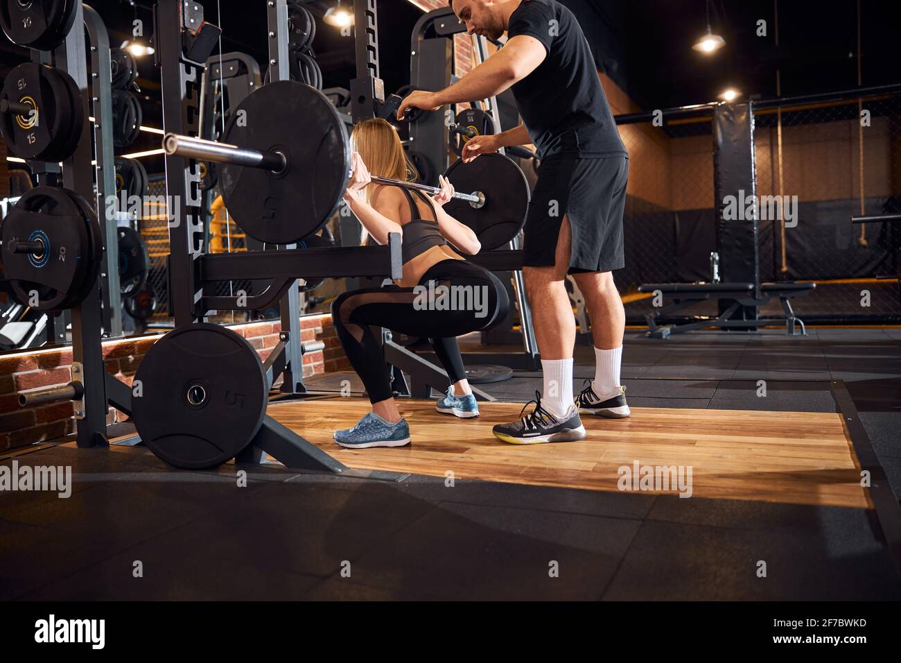 Professional fitness coach helping woman with weight-lifting Stock ...
