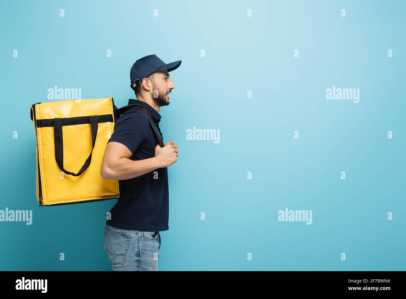 side view of muslim delivery man carrying thermo backpack on blue Stock ...