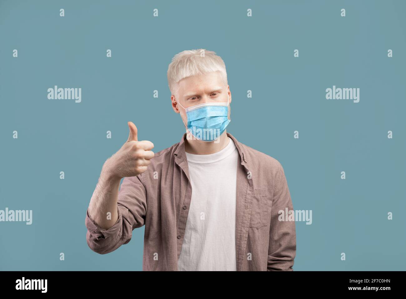 Stay safe. Albino man in medical protective mask showing thumb up on ...