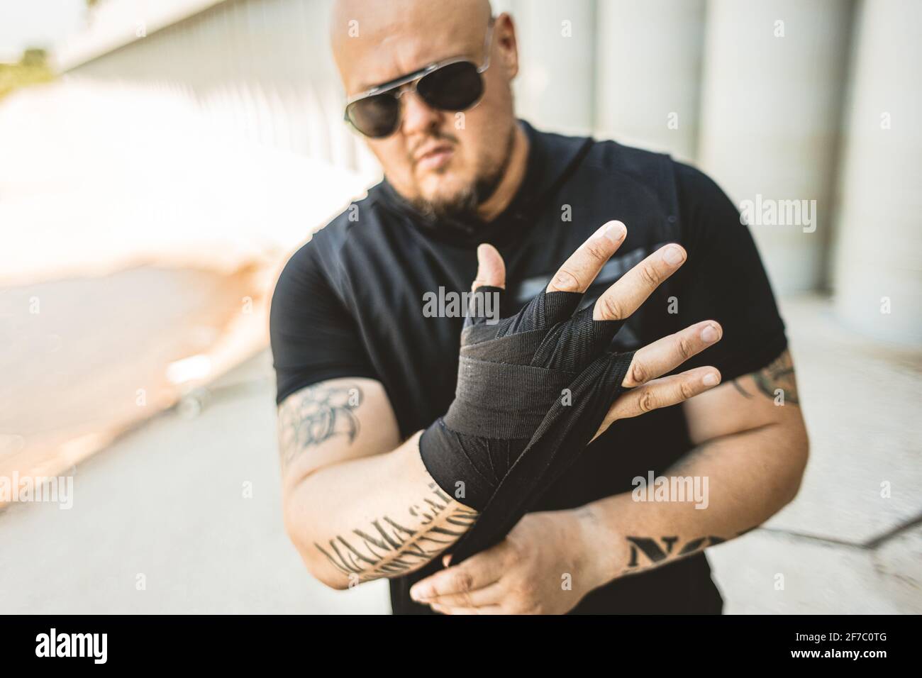 Boxer wrapping up his hands boxing bandages before a match, fight or ...